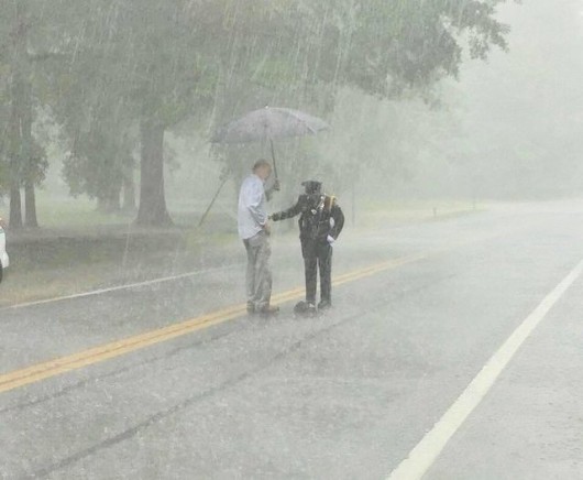 Police Officer Stands in the Pouring Rain With a Smile as She Protects ...